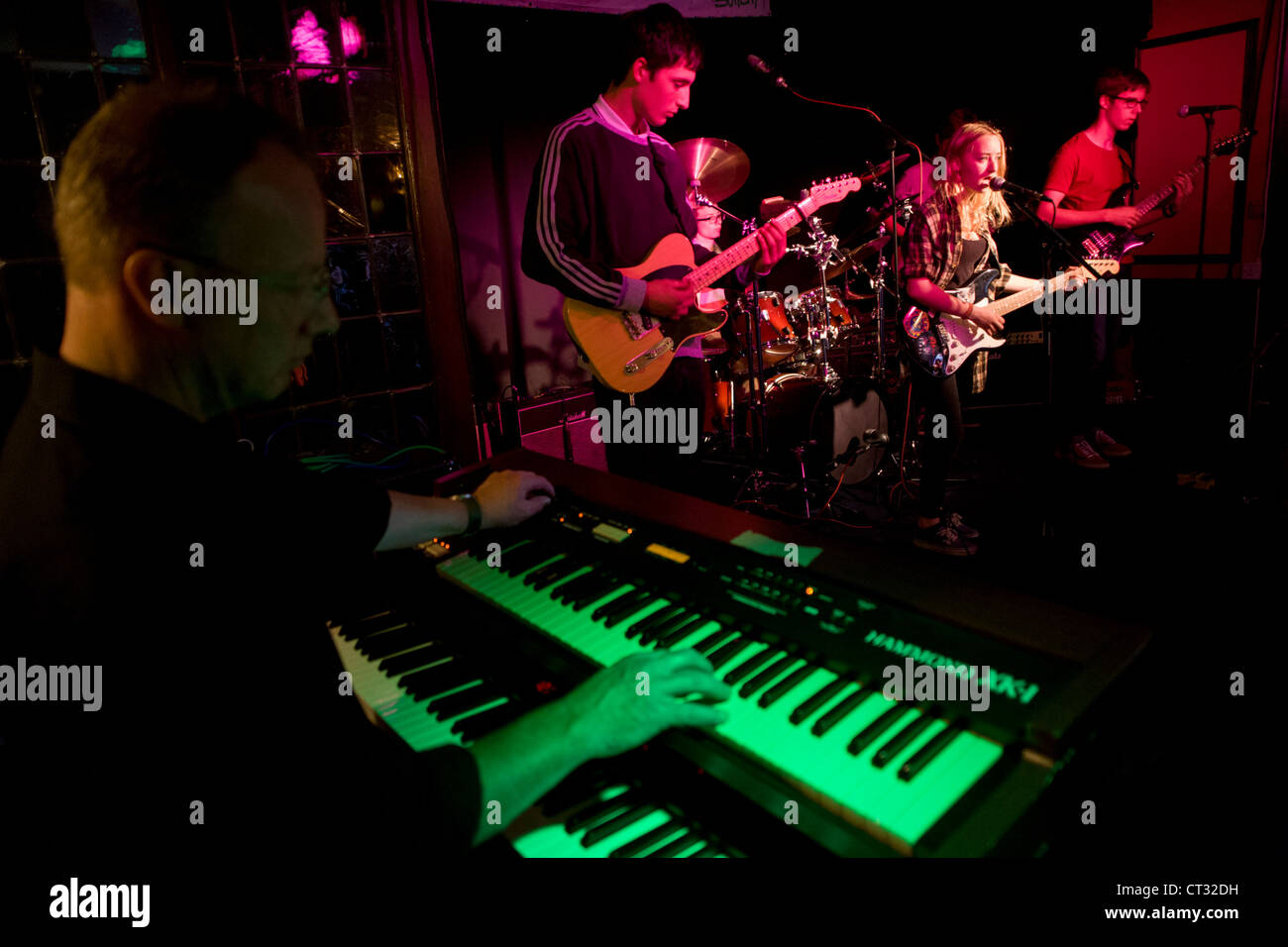 Adult keyboard player accompanies a teenage band perform band in a ...