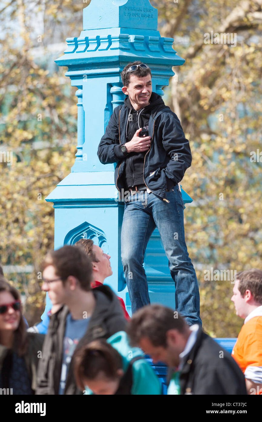 A spectator stands on the railings of Tower Bridge to get a better view ...