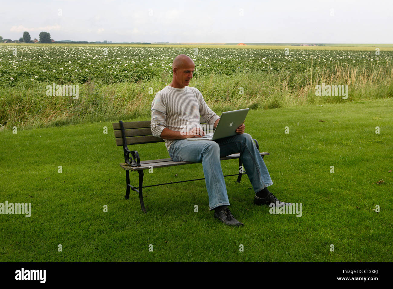 Man with Apple laptop sitting in the garden, with wide view Stock Photo ...