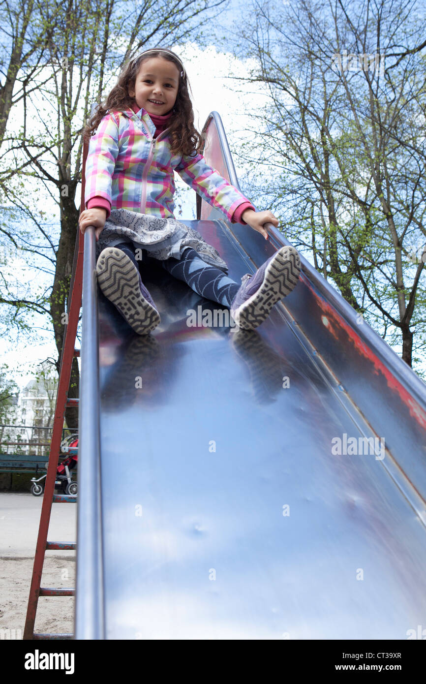 Girl playing on slide in playground Stock Photo - Alamy