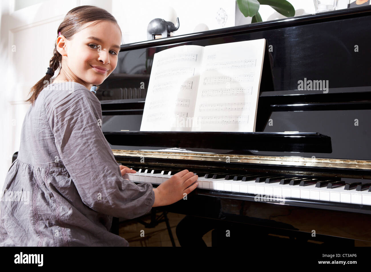 Smiling girl practicing at piano Stock Photo - Alamy