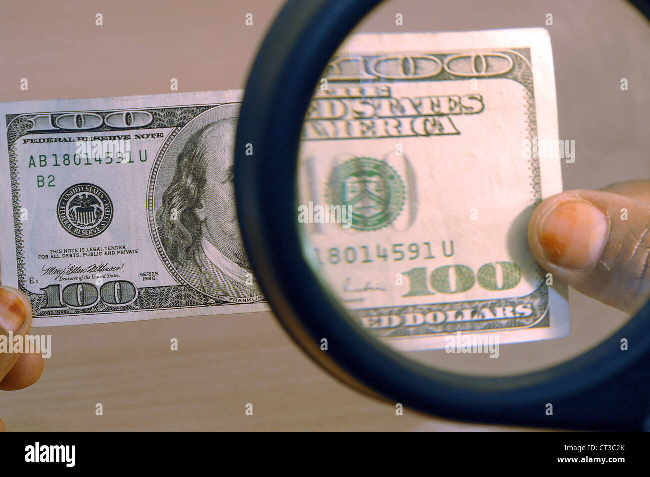 A scientist examining a possibly counterfeit one hundred dollar bill ...