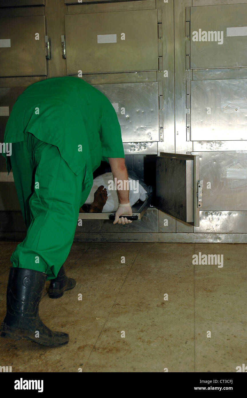A mortuary technician places a human body in a cold storage facility ...