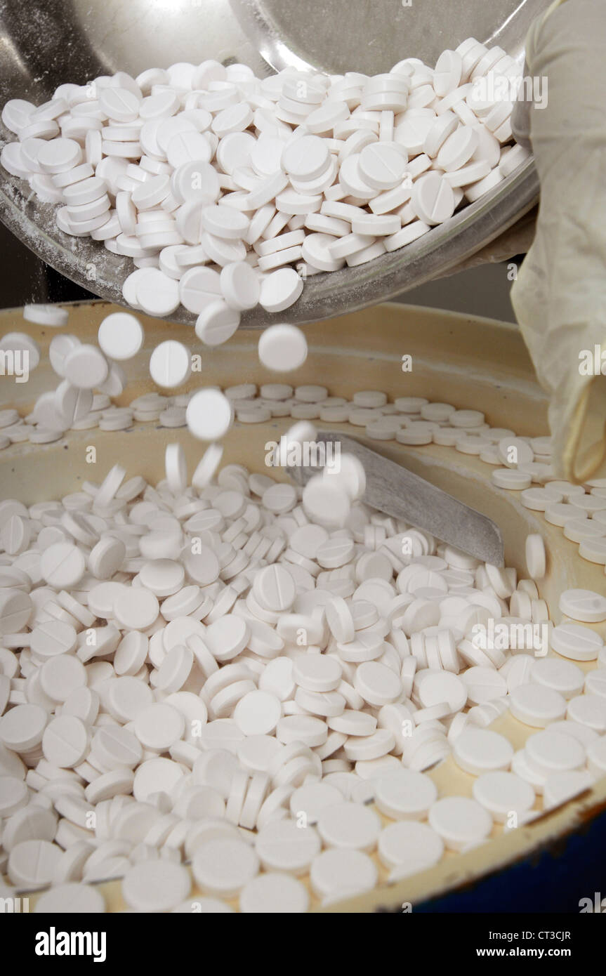 Drug production. Drug tablets spill into a container on part of a ...
