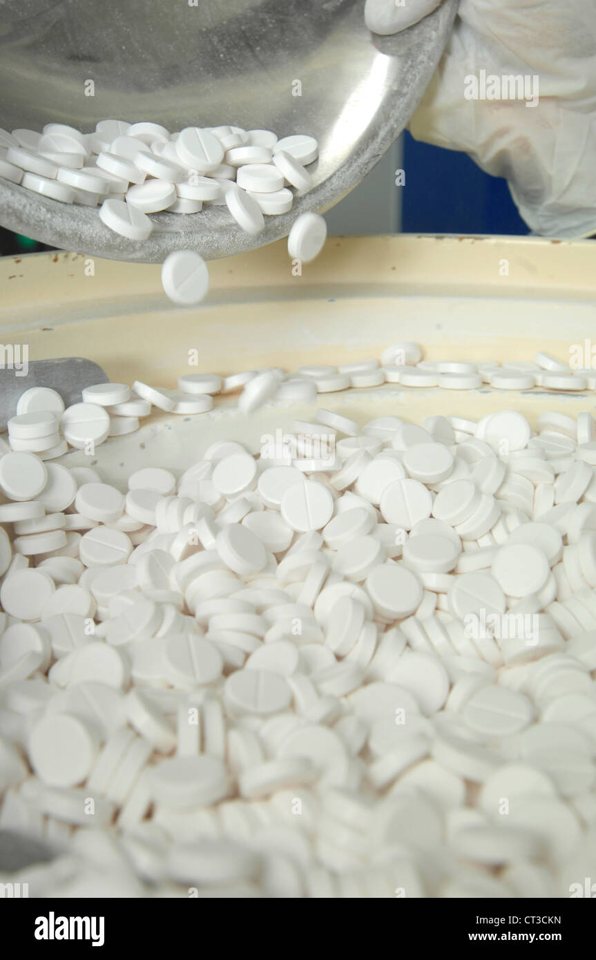 Tablets spilling off a production line into a container Stock Photo - Alamy
