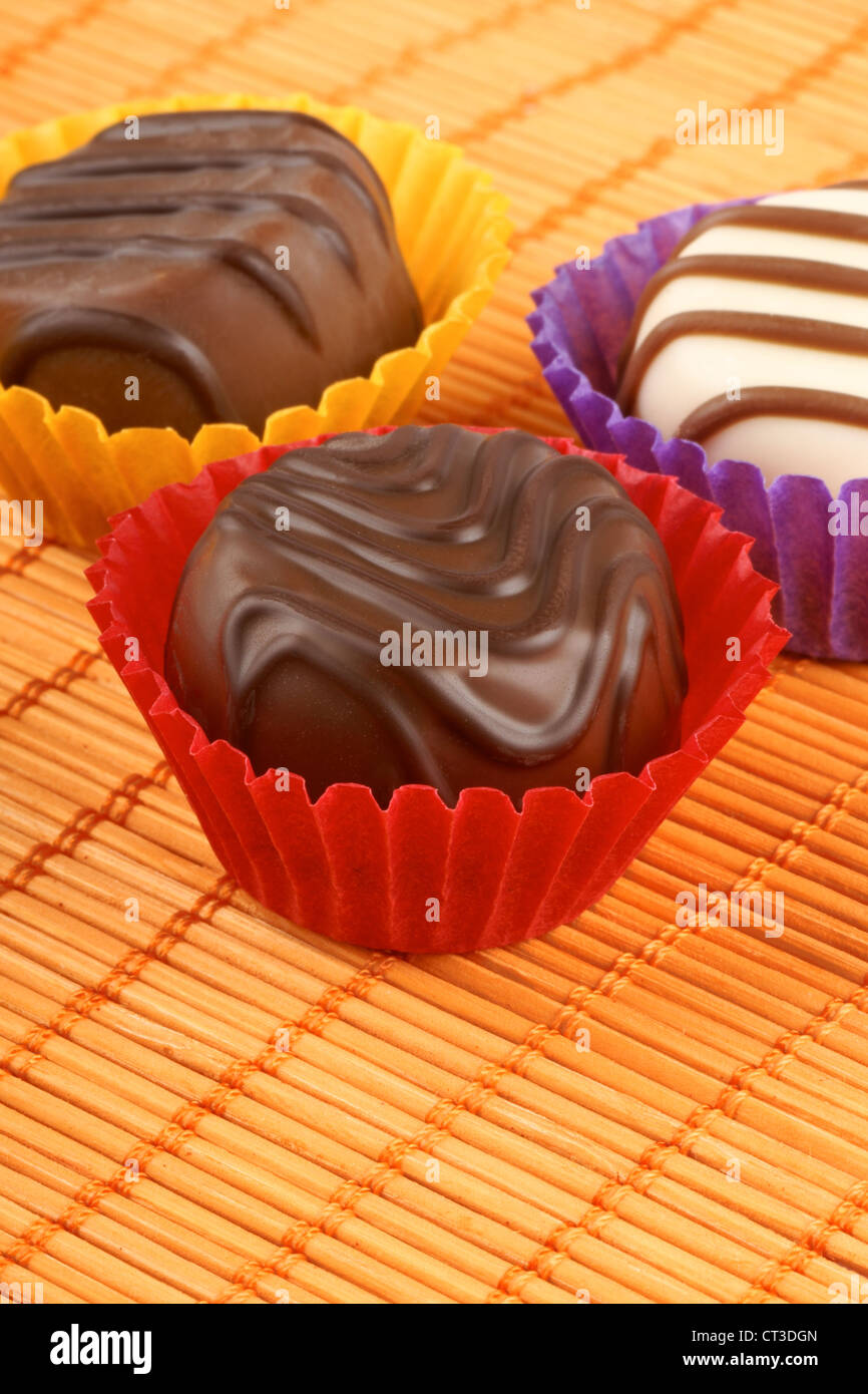 Closeup of some mixed chocolate pralines over an orange background ...