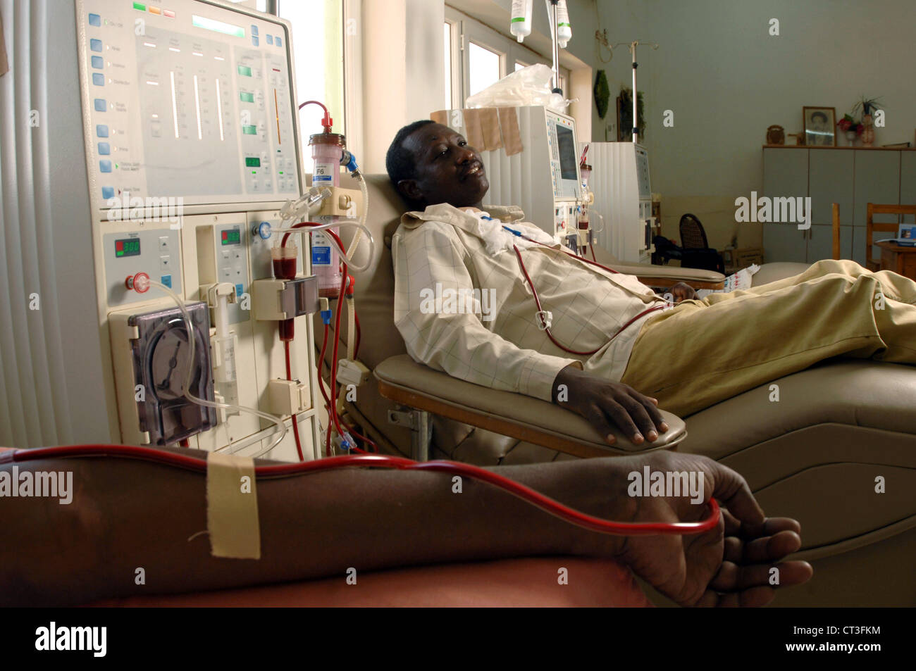 A man lays patiently while attached to a dialysis machine. The image ...