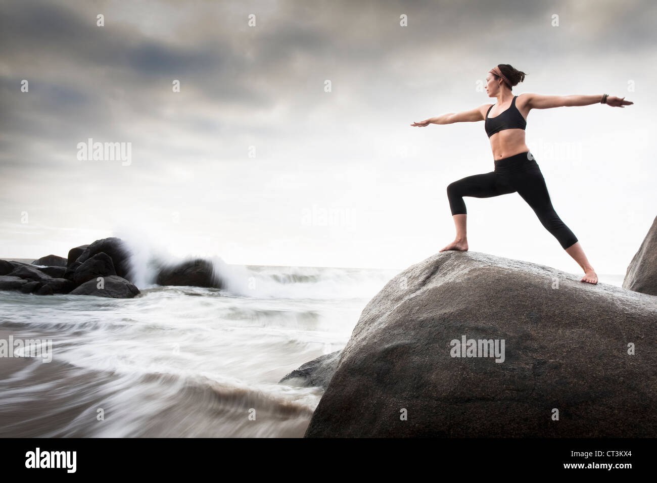 Woman practicing yoga on rocks on beach Stock Photo - Alamy