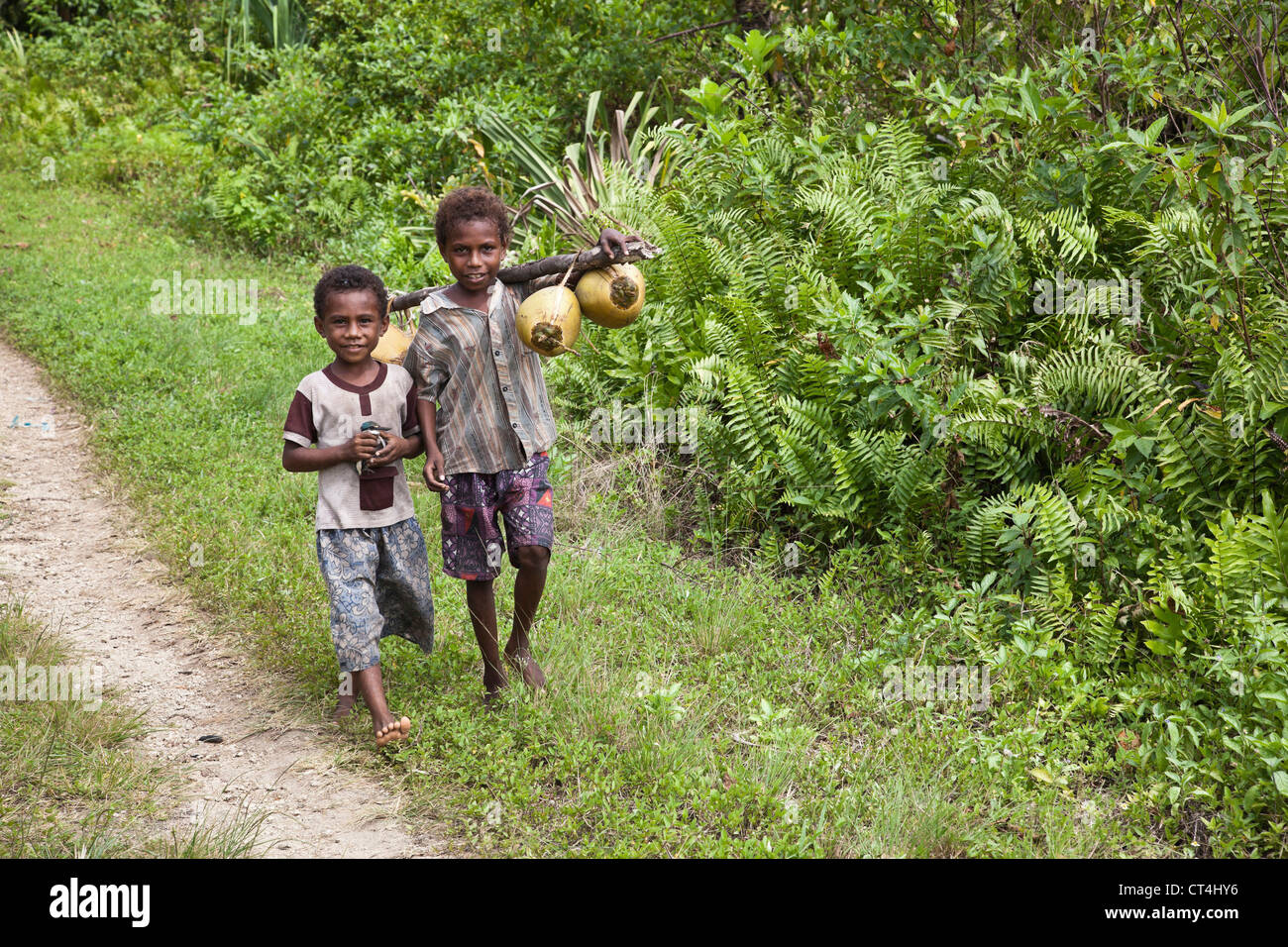 Indonesia, Papua New Guinea, Kitava Island. Two young boys walking down ...