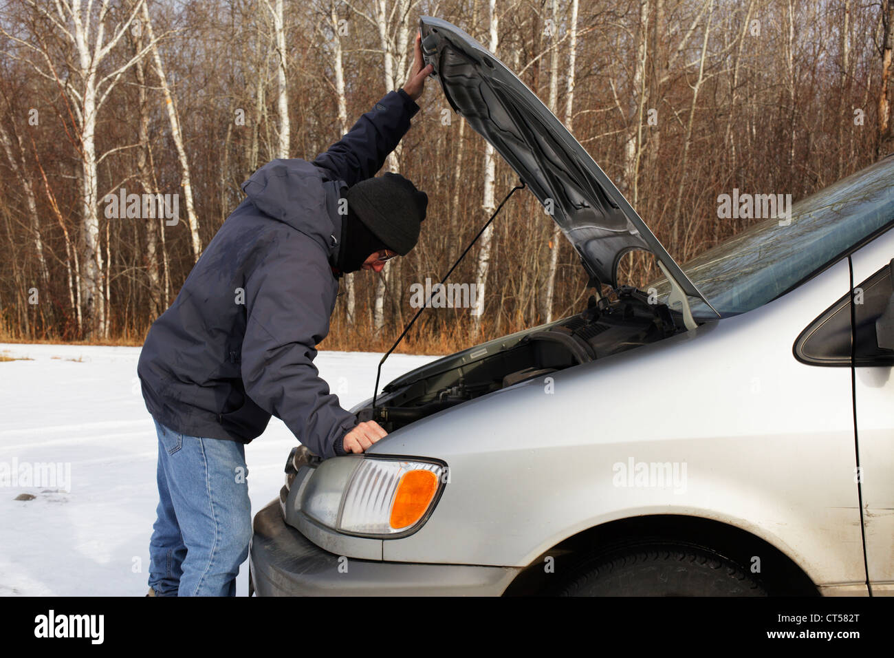 Man looking under the hood of a vehicle in winter Stock Photo - Alamy
