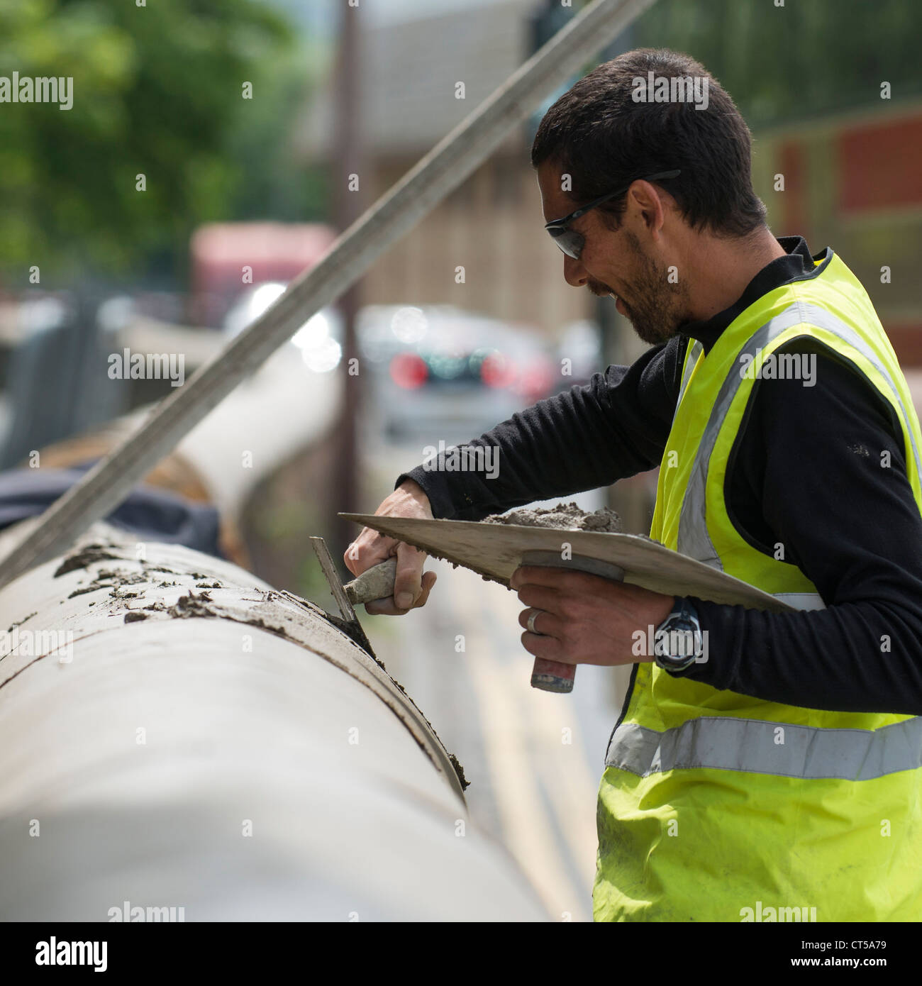 A workman trowelling cement on to relaid wall hi-res stock photography ...