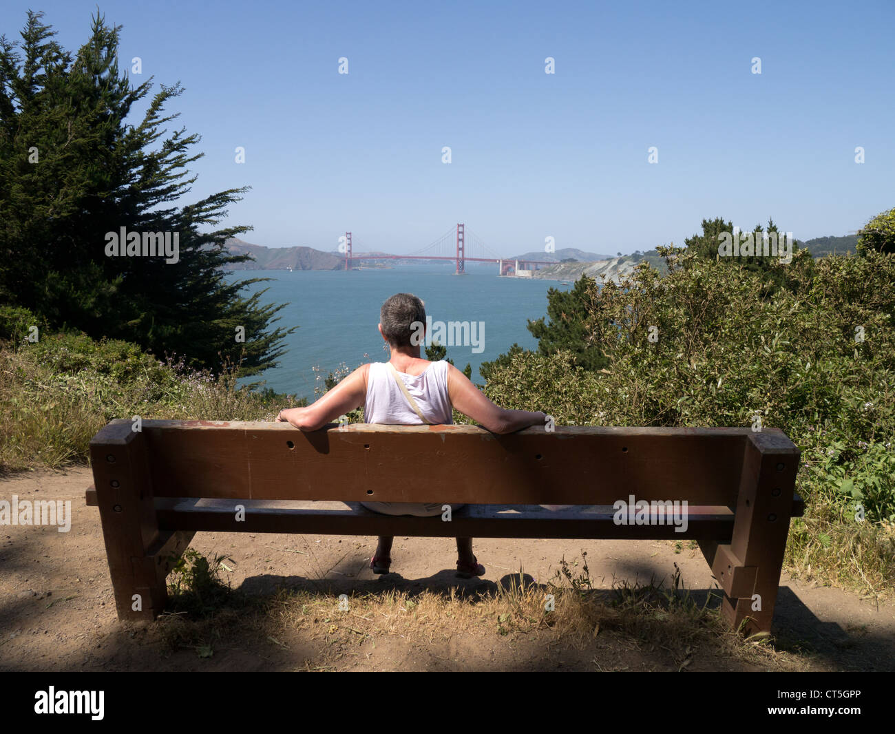 Woman sitting on bench looking at the Golden Gate Bridge,San Francisco ...