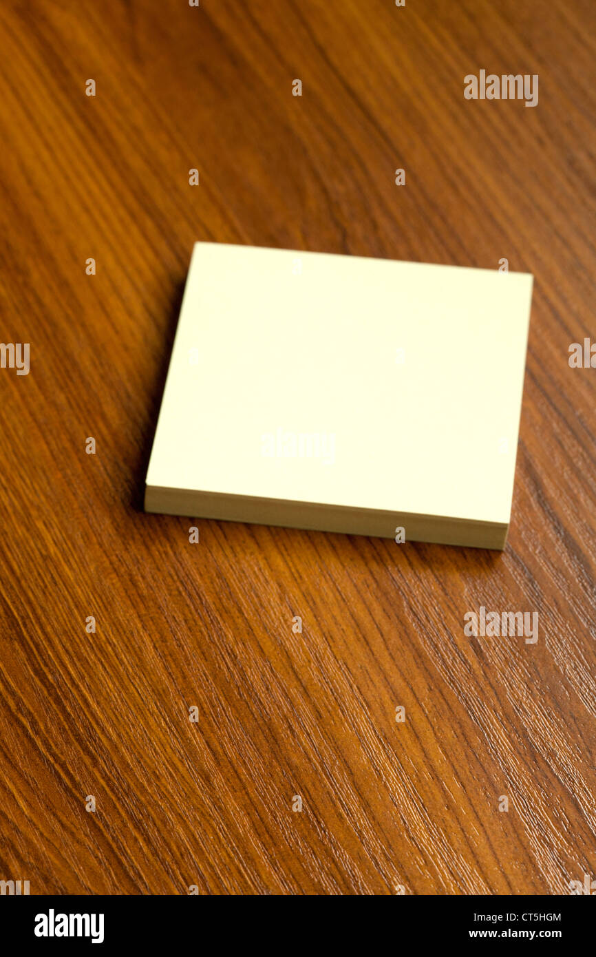 Yellow post it pad on a desk Stock Photo - Alamy