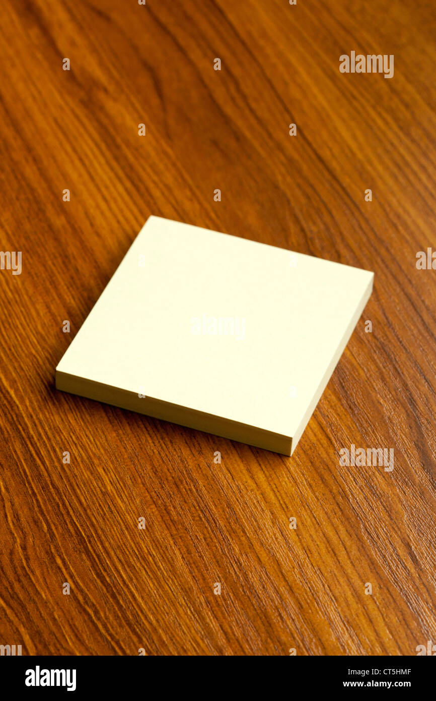 Yellow post it pad on a desk Stock Photo - Alamy