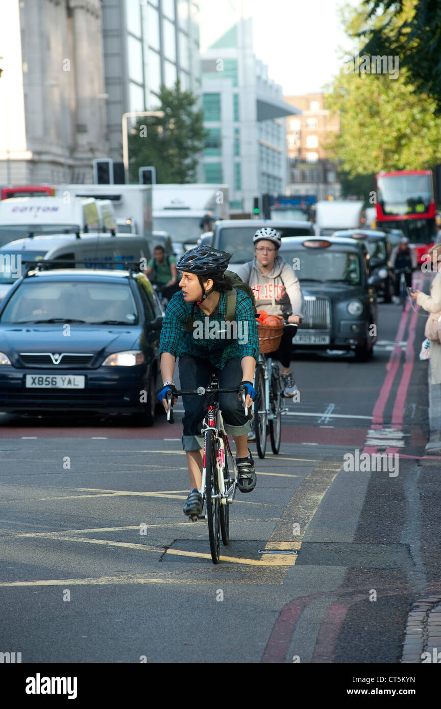Cyclists riding through busy traffic in the city of London, England ...