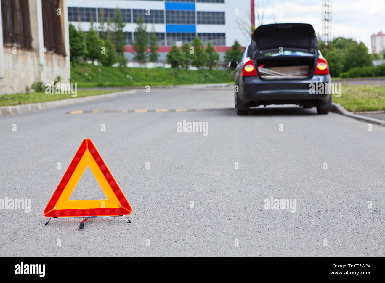 Triangle warning sign on road foreground and broken car with blinker ...