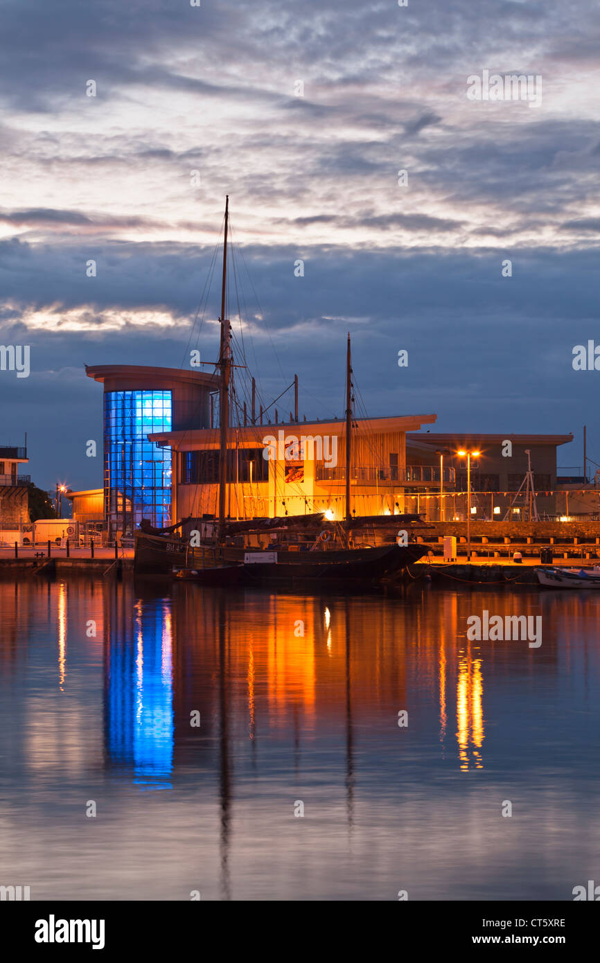 Brixham Fish market at dusk, reflecting in the still water of the inner ...