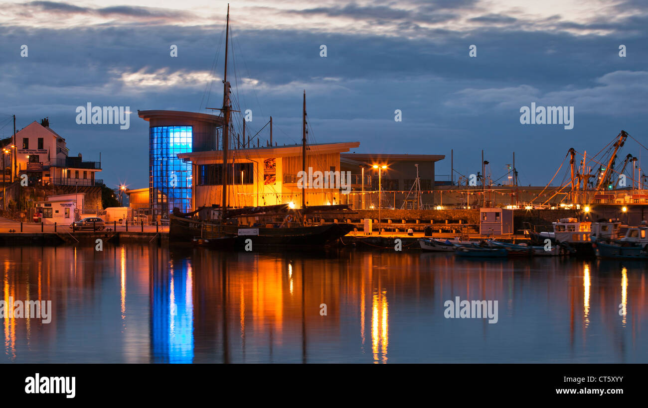Brixham Fish market at dusk, reflecting in the still water of the inner ...