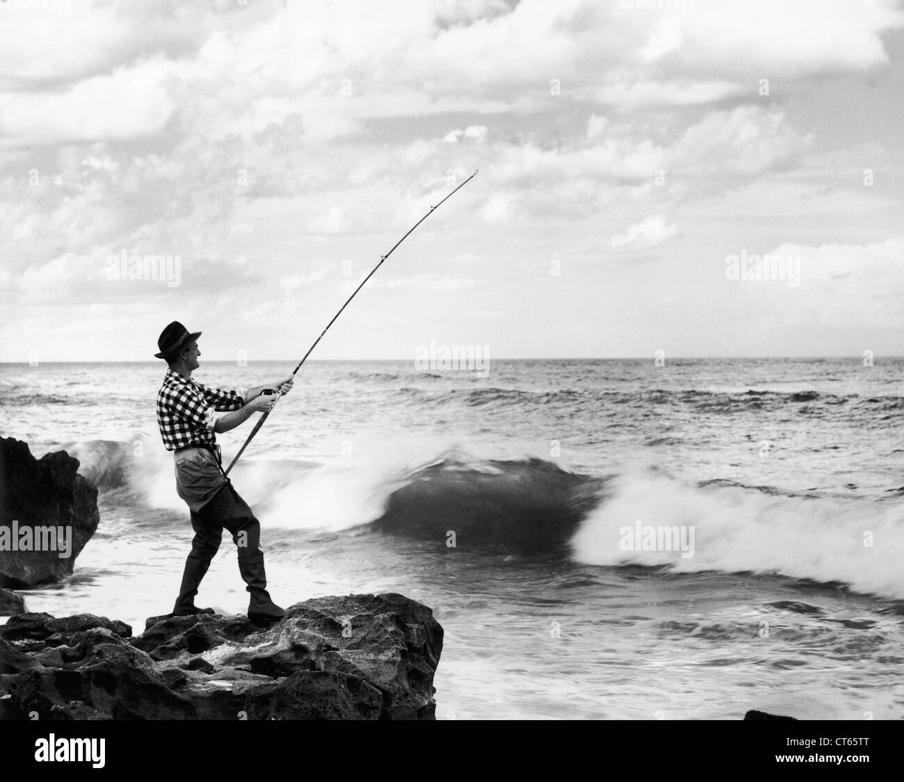 Man fishing in ocean from rock Stock Photo - Alamy