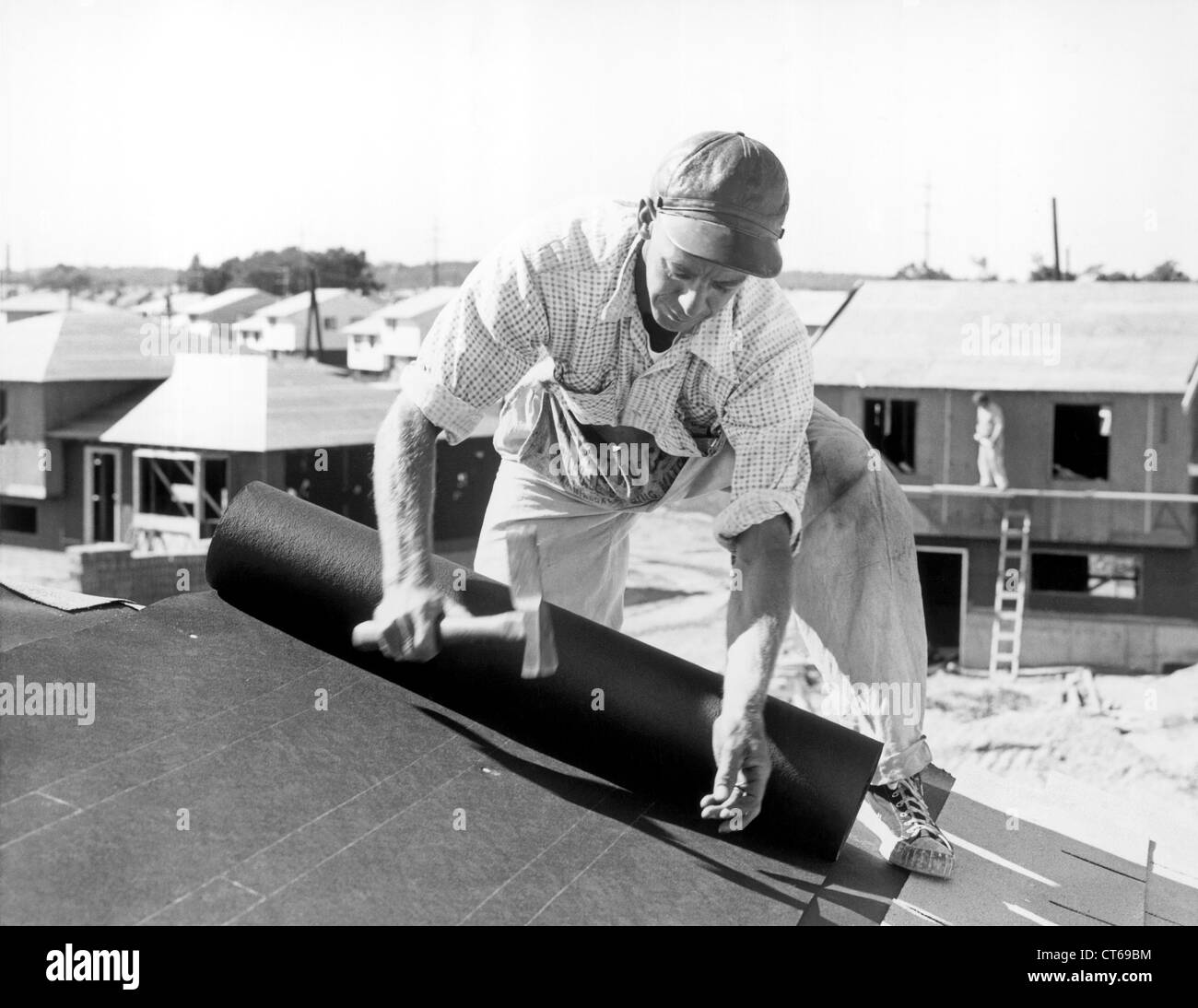 Construction worker working on roof of house Stock Photo - Alamy