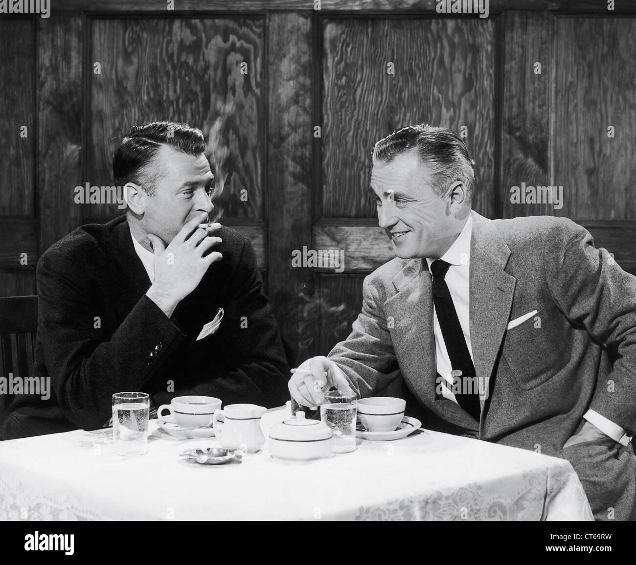 Businessmen smoking cigarettes and smiling at dinner Stock Photo - Alamy