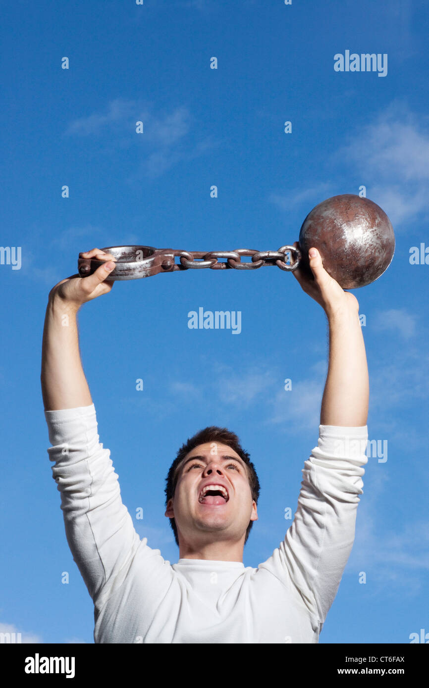 Young man holding metal shackle against blue sky Stock Photo - Alamy