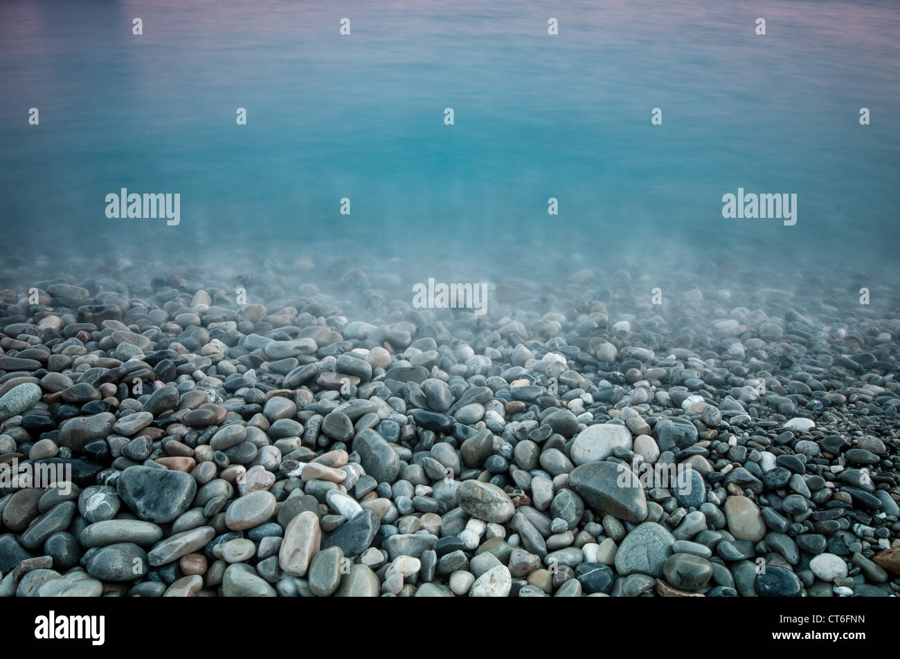 pebble stones by the sea. Silky waves of blue sea from long exposure ...