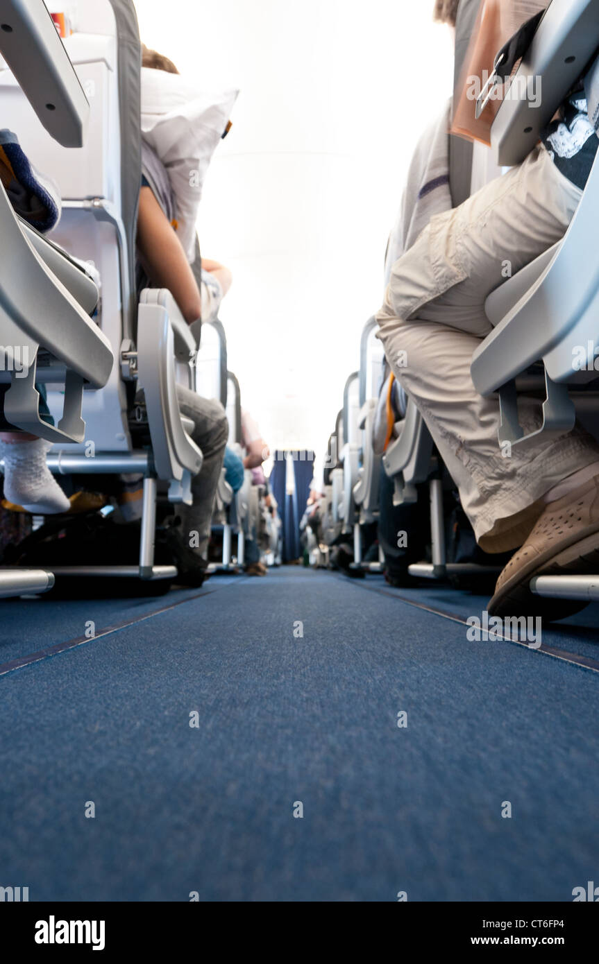 Low angle view of air plane cabin aisle with rows of seats by the sides ...