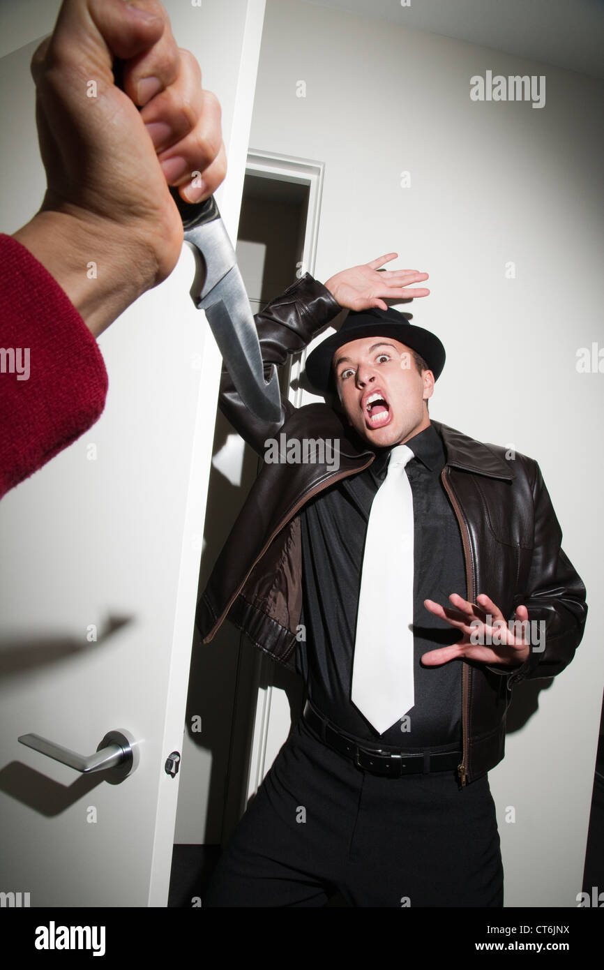 Young man surprised by looking at burglar entering the room with knife ...