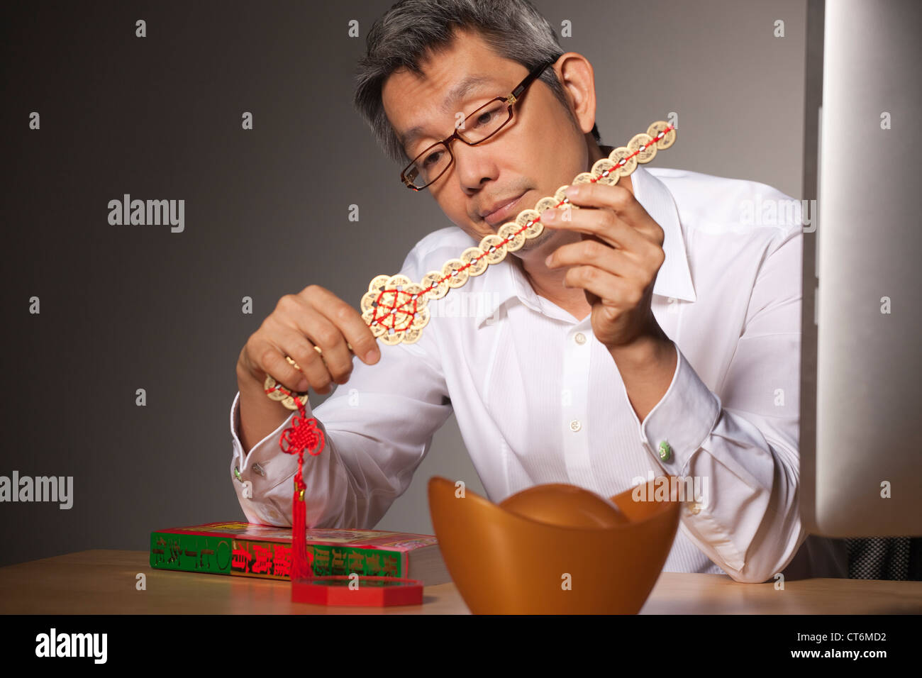 Thoughtful Chinese man looking at feng shui accessories on table Stock ...