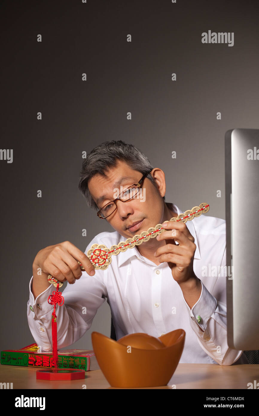 Thoughtful Chinese man looking at feng shui accessories on table Stock ...