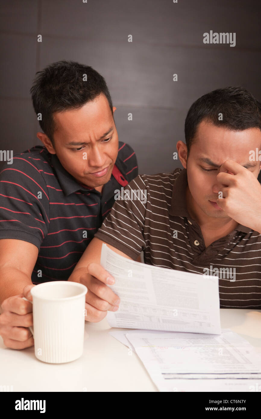Worried homosexual couple looking at paperwork on desk Stock Photo - Alamy