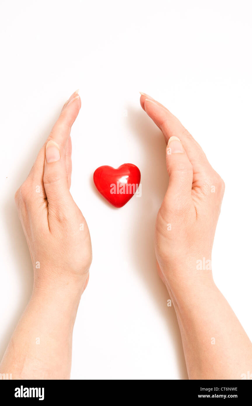 female hands in gesture of protecting an heart shape, caring for love ...