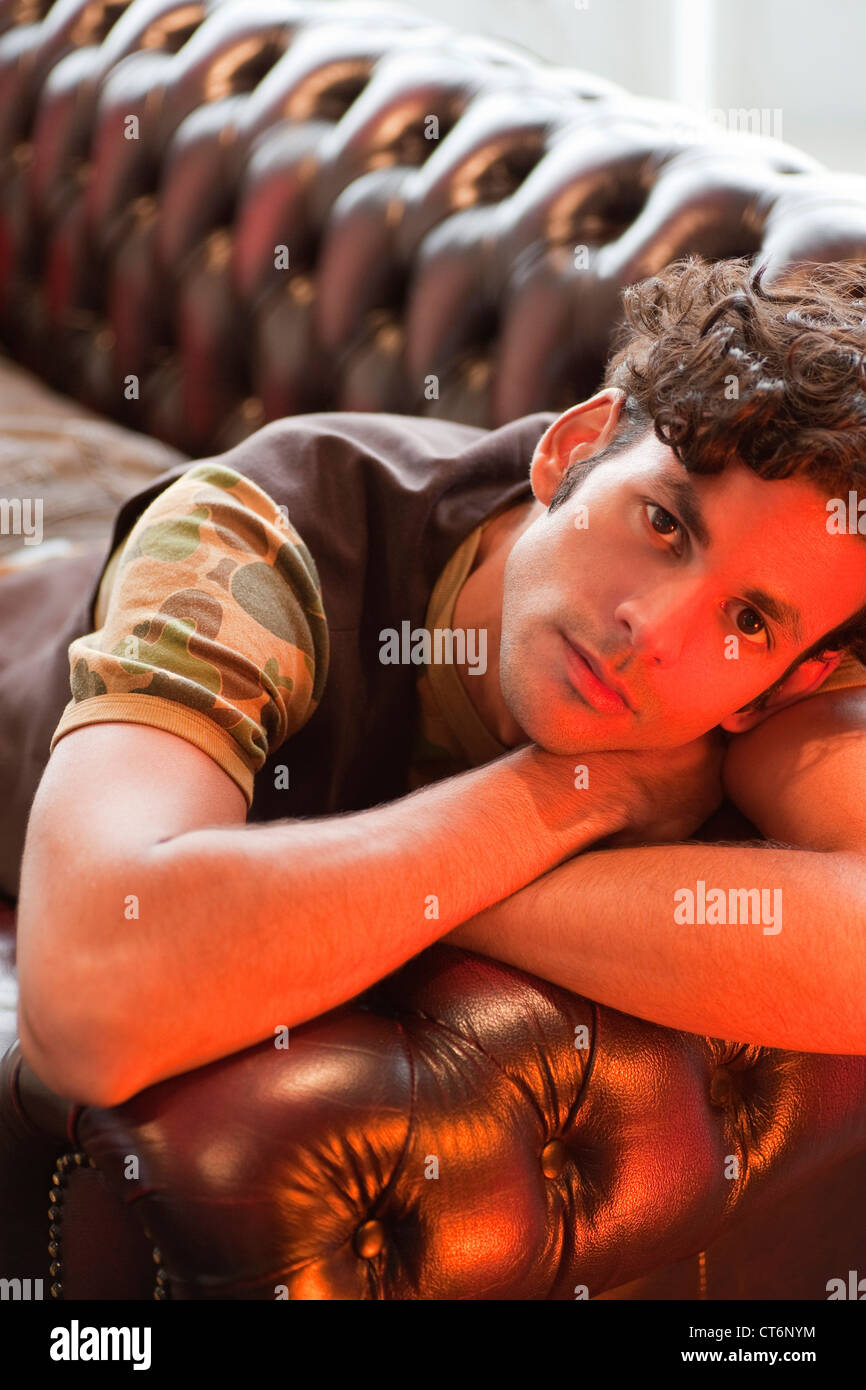 Portrait of a thoughtful young man lying on couch Stock Photo - Alamy