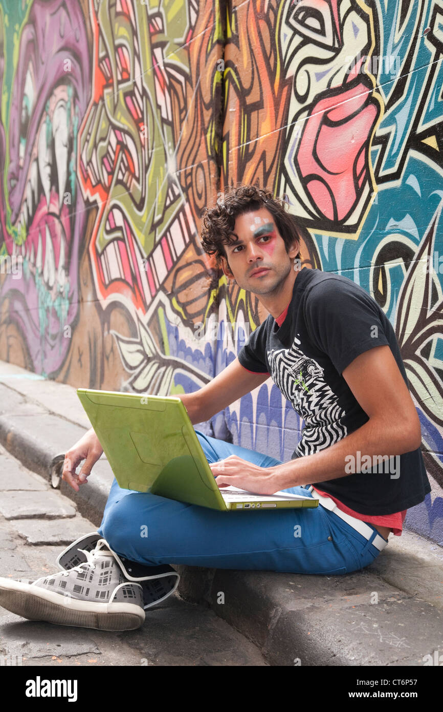 Serious young man using laptop in front of graffiti art Stock Photo - Alamy