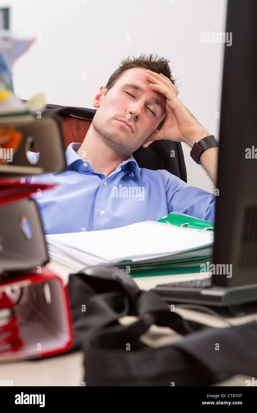 Exhausted office worker falls asleep in front of his computer ...