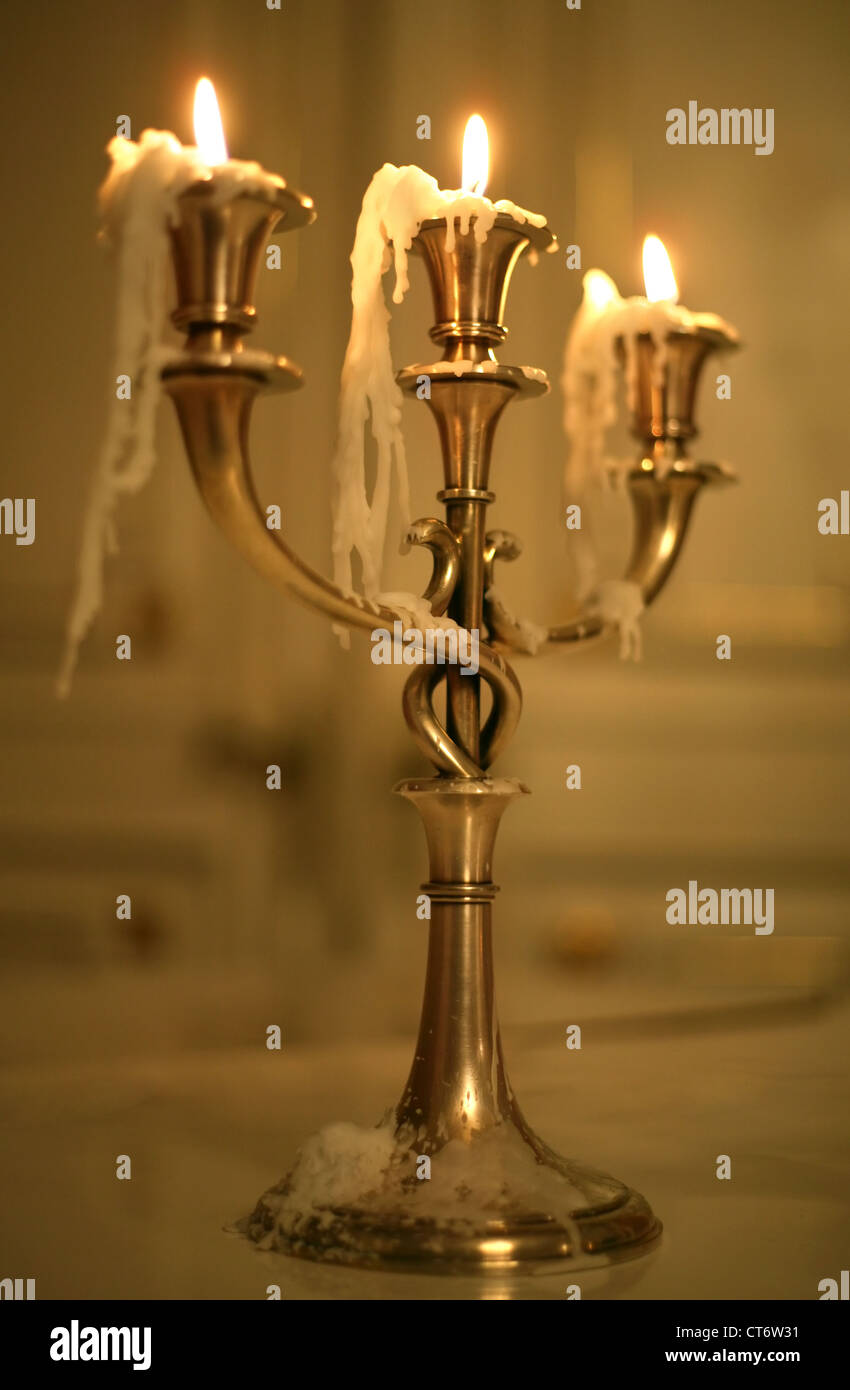 Three burning candles in an ancient gold candelabrum Stock Photo - Alamy