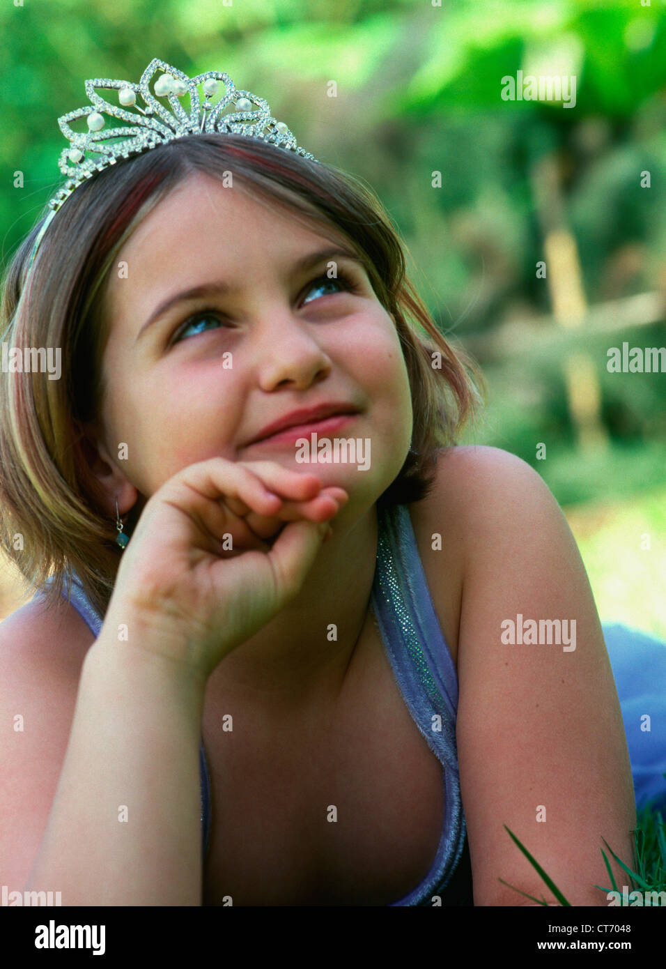 A young girl laying in the grass wearing a tiara. (8-10 years old Stock ...