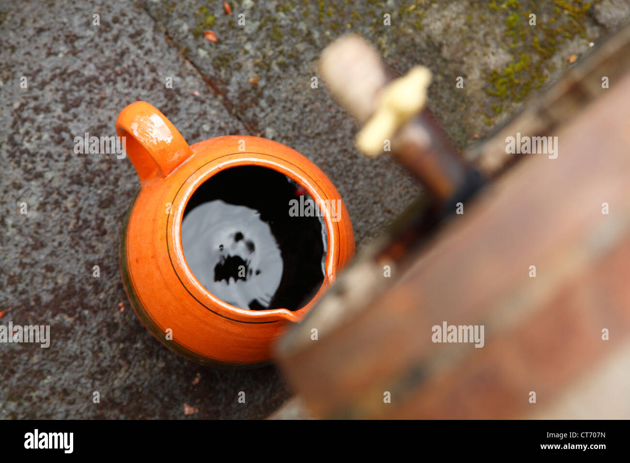 Wine dripping from barrel into ceramic pitcher Stock Photo - Alamy