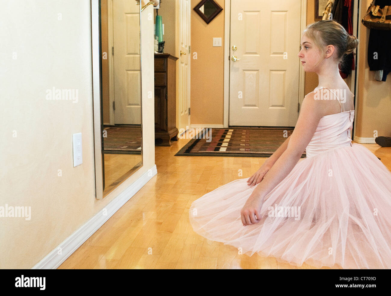 A young girl practicing ballet at home studying herself in the mirror ...