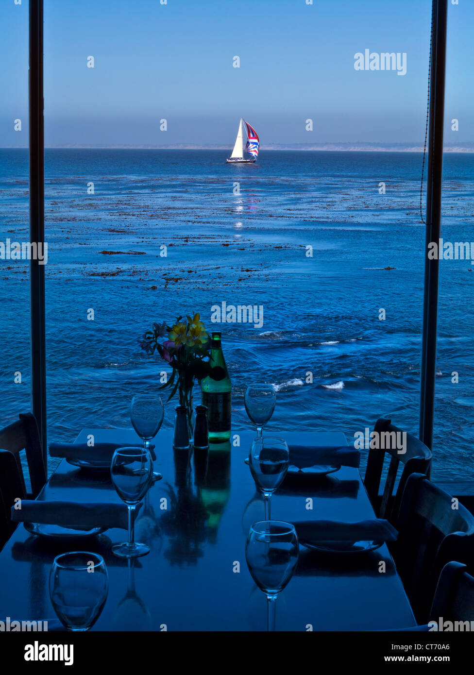 Table setting in coastal sea view restaurant with kelp fields and yacht ...