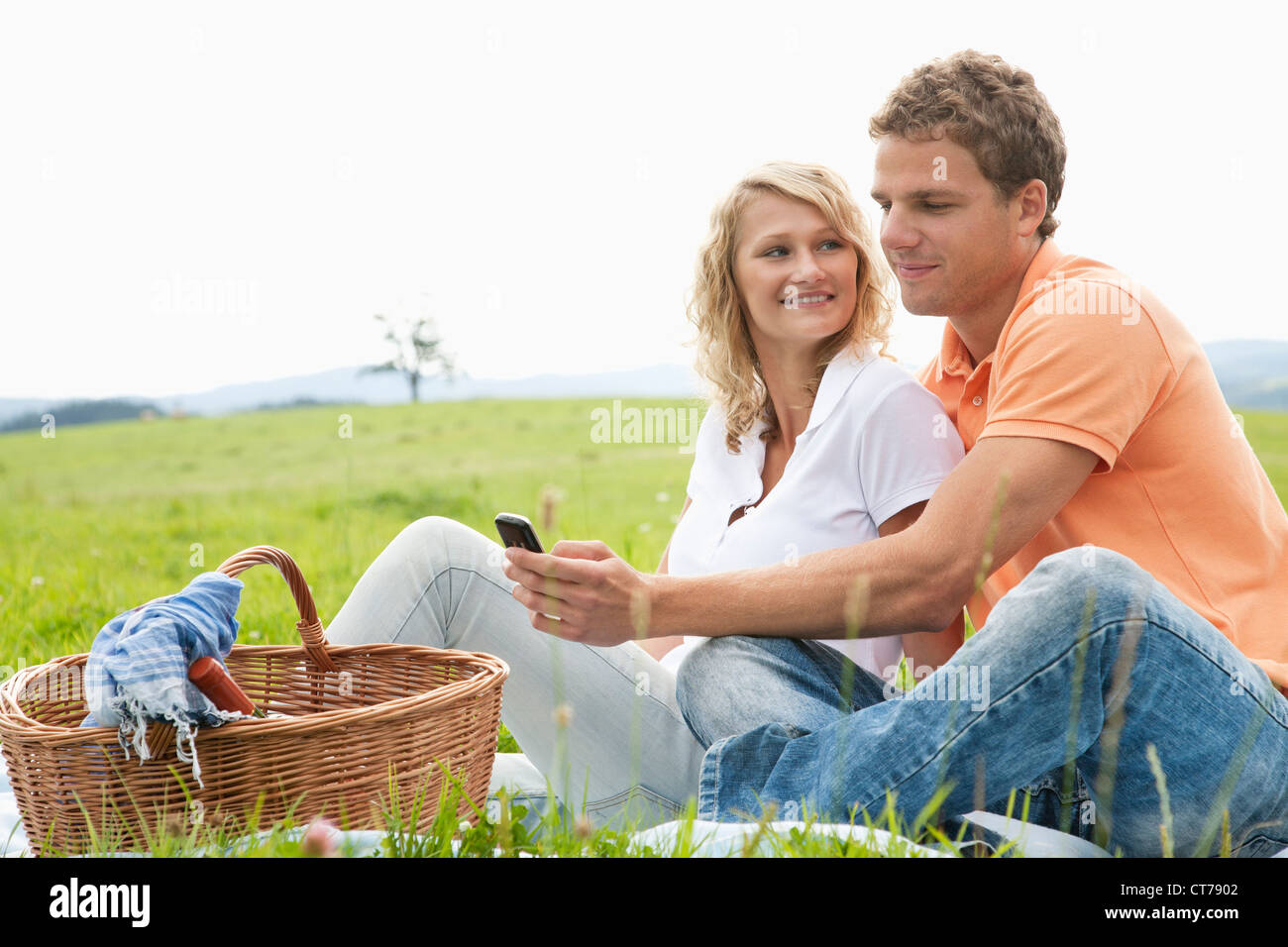 young couple having picnic looking at display of mobile phone Stock ...
