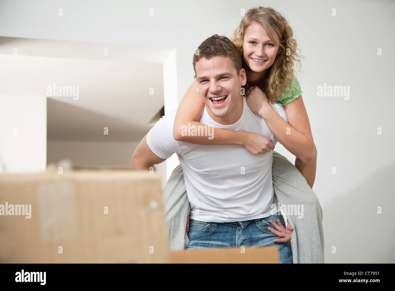 young man giving woman piggback ride in new home Stock Photo - Alamy