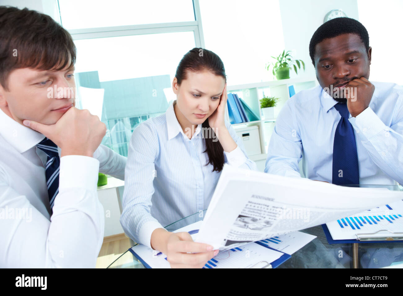 Three bored colleagues reading newspaper in office Stock Photo - Alamy
