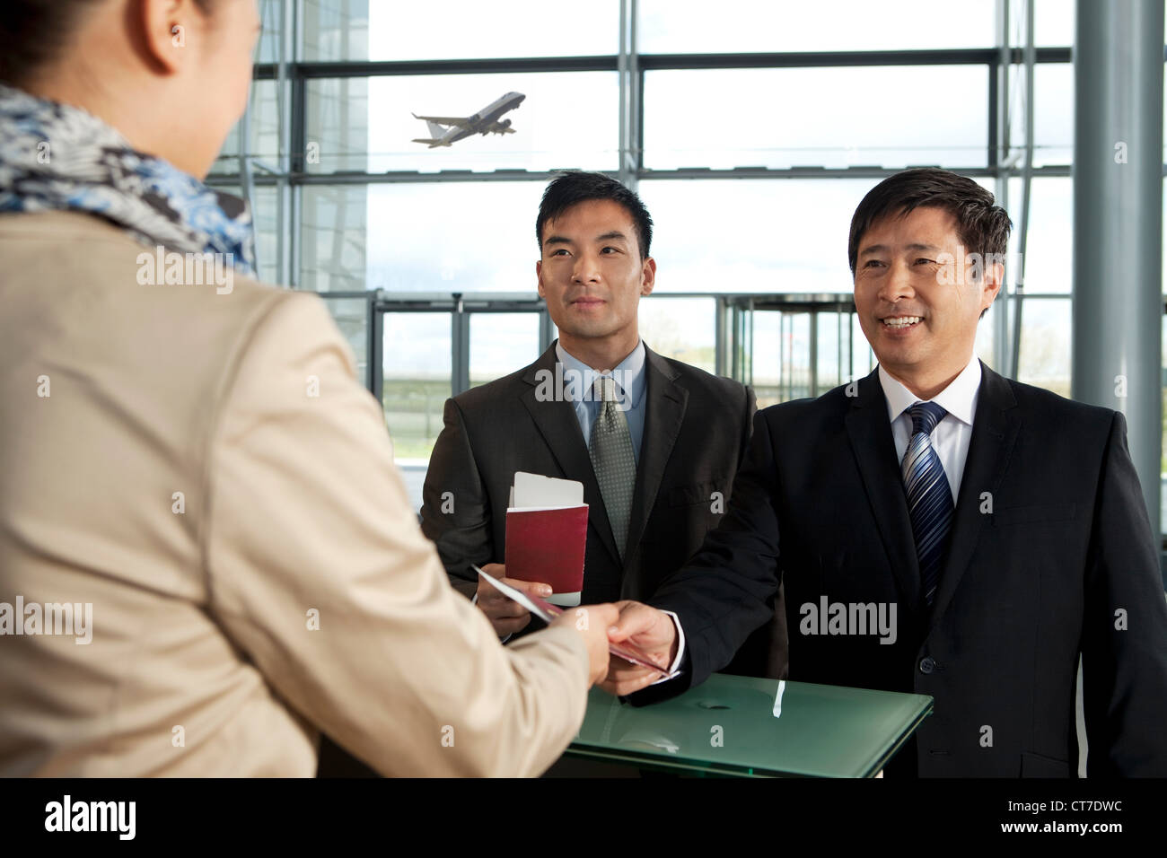 Businessmen checking in at airport Stock Photo - Alamy