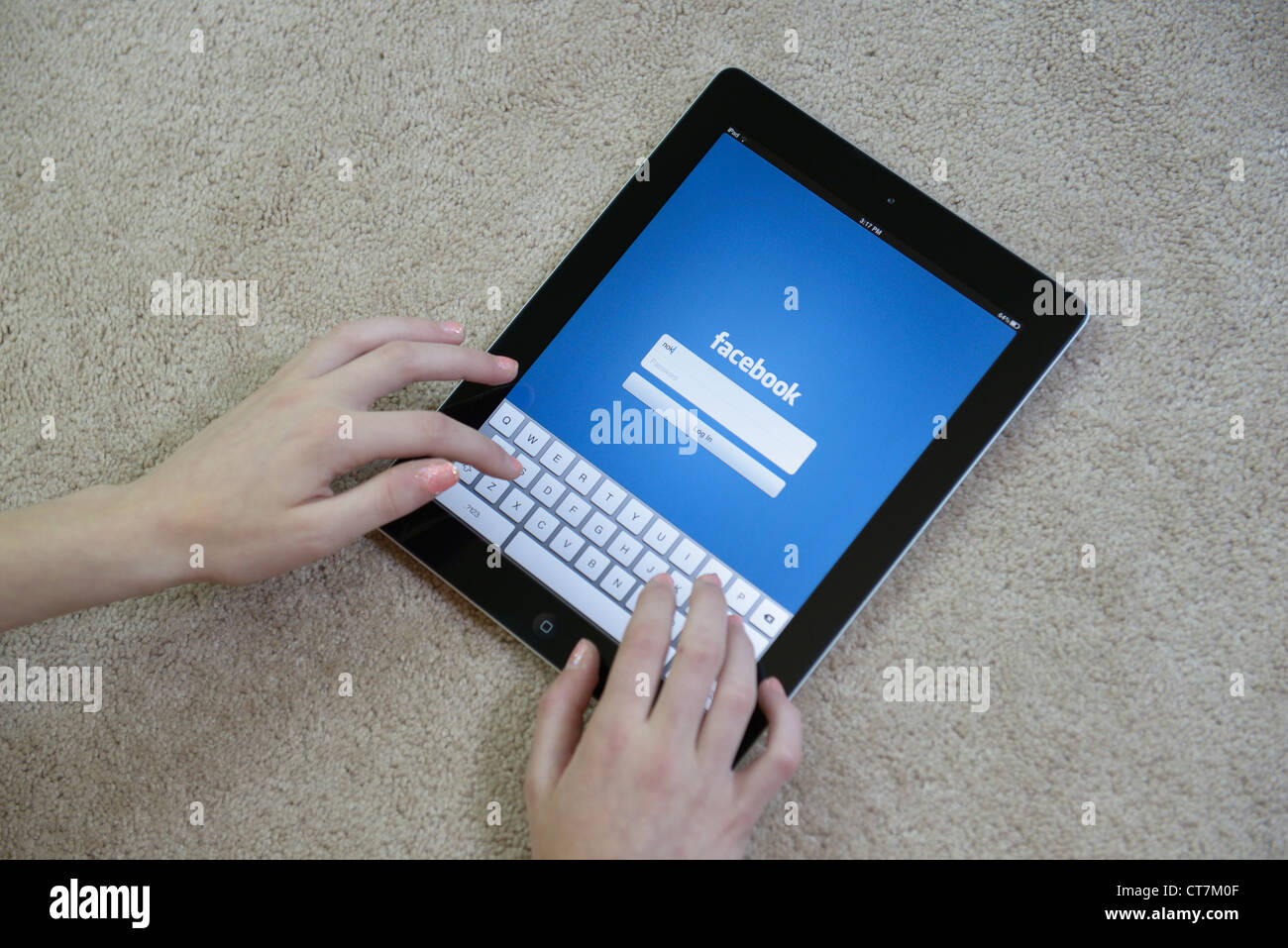 Girl typing password onto iPAD keyboard to access Facebook Stock Photo ...