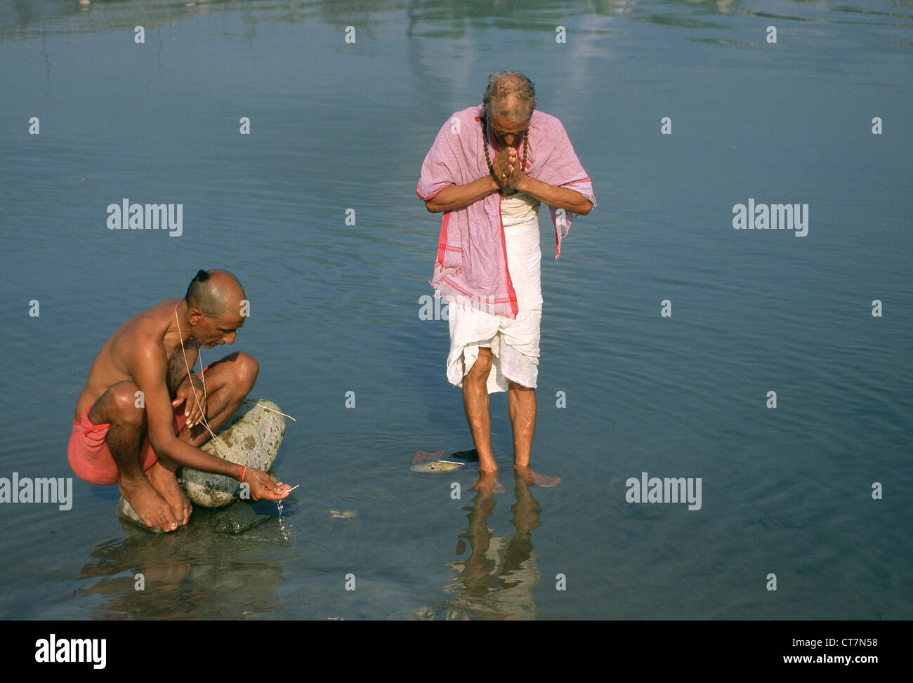 Two hindu men are praying in a river. They are worshiping the Sun god ...