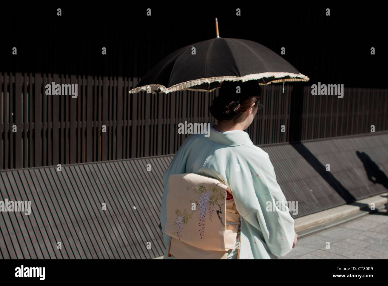A woman holding an umbrella dressed in traditional Geisha clothes in ...