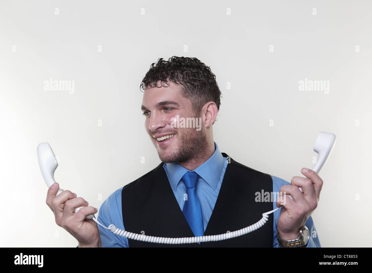 handsome man holding up two phones connected by a single telephone wire ...