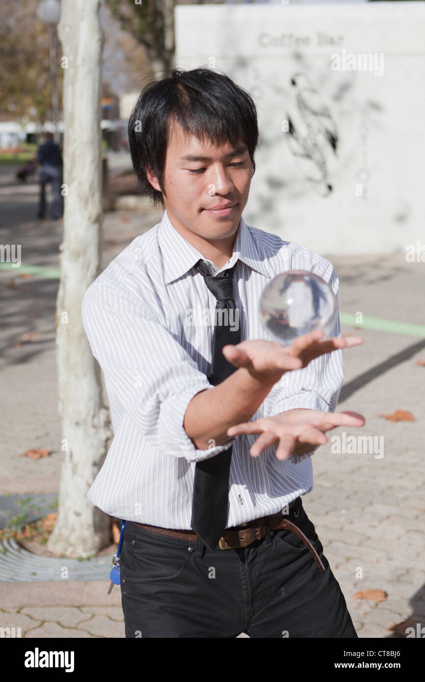 Shirt and tie wearing street performer with a glass orb ball ...